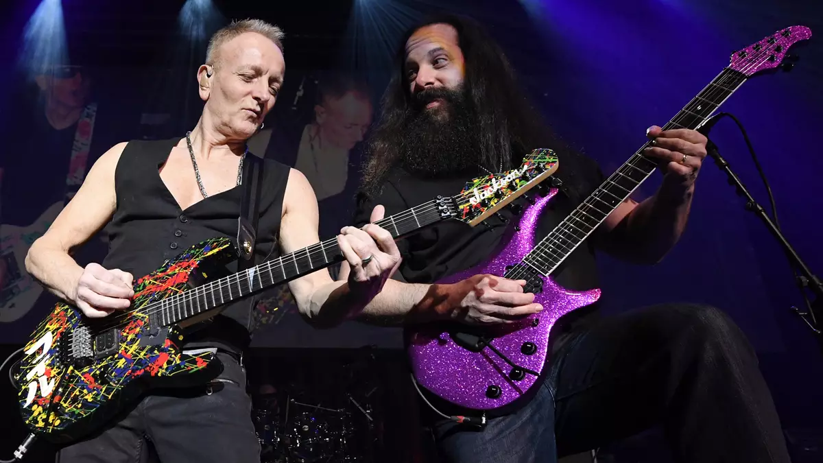 Gitaris Phil Collen (L) lan John Petrucci tampil minangka bagéan saka tur konser G3 ing Brooklyn Bowl Las Vegas ing The Linq Promenade tanggal 17 Januari 2018 ing Las Vegas, Nevada.